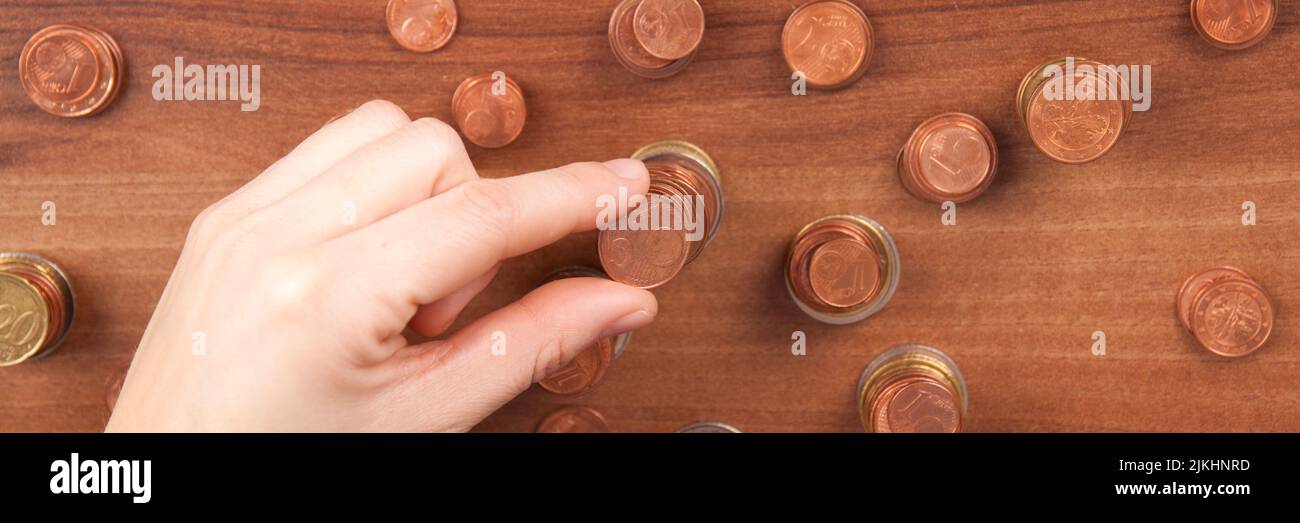 A top view closeup of a human counting his stacks of coins savings ...