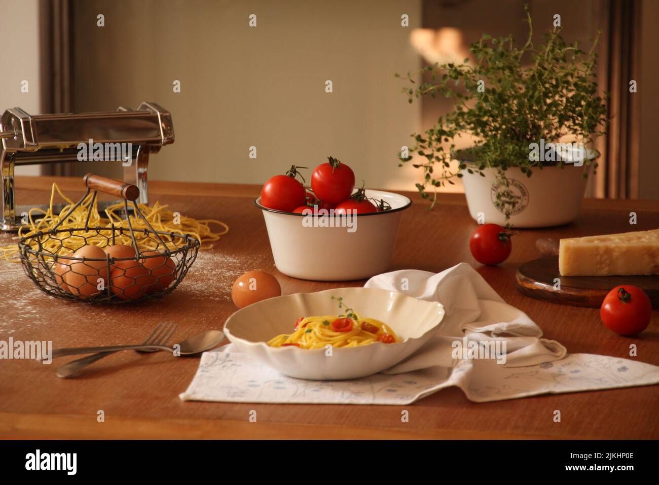 Still life of a wooden kitchen table with cooked pasta, raw eggs, and ...