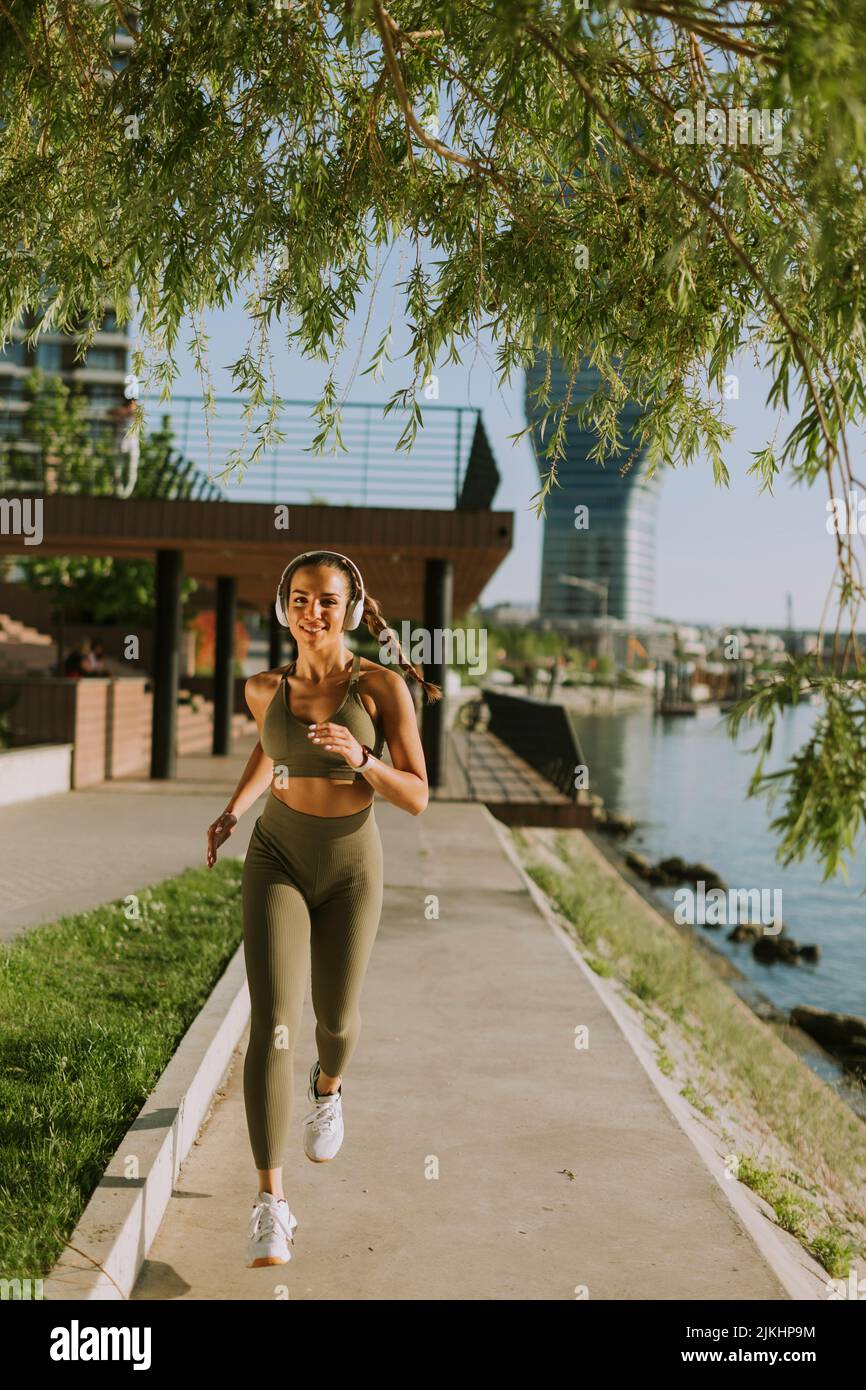 View at active young beautiful woman running on the promenade along the ...