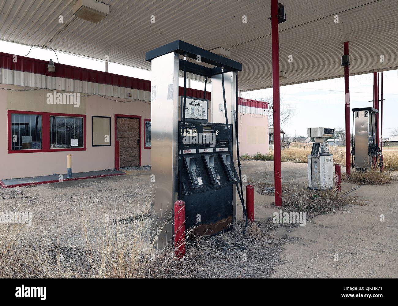 A side view of an old abandoned gas station with rusty pumps and ...