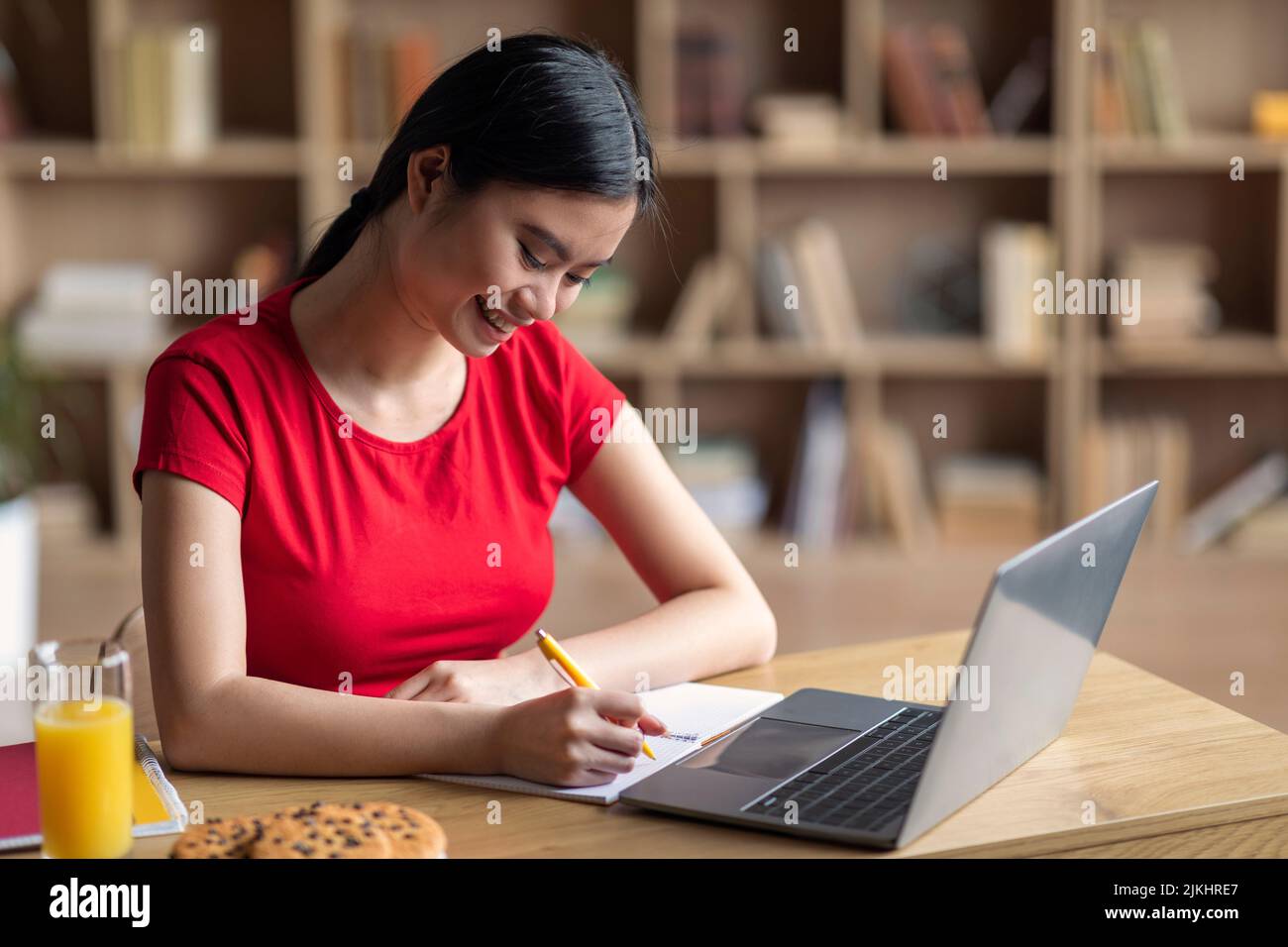 Knowledge and homework. Smiling young asian female student with laptop ...