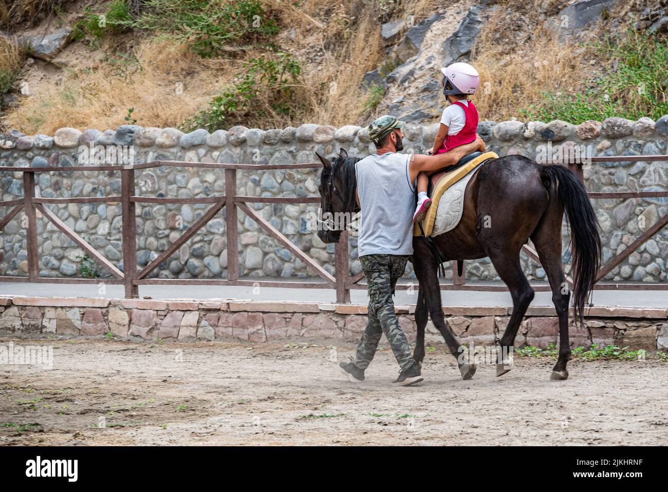 A beautiful shot of an adult man teaching little kid how to ride a ...