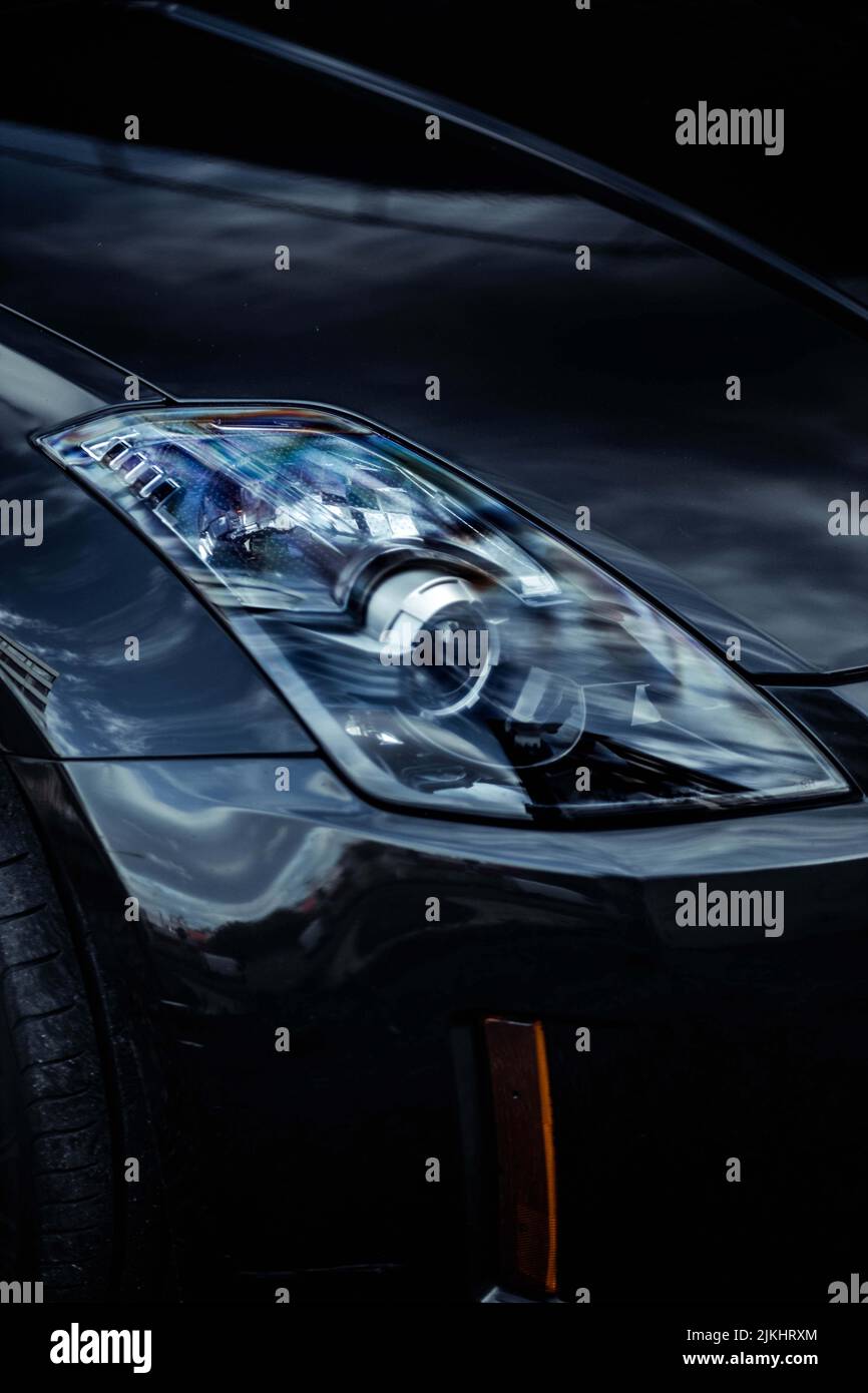 A vertical closeup shot of a headlight on a black car Stock Photo - Alamy