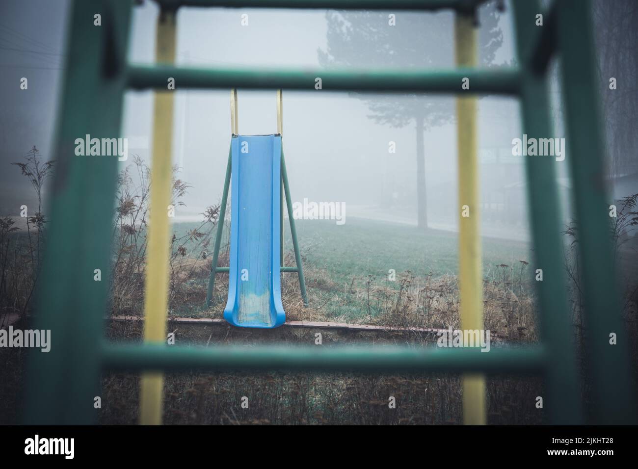 A blue children's slide in a playground on a foggy day Stock Photo - Alamy