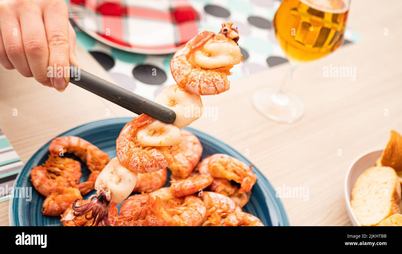 woman takes shrimp with tongs from a large plate of seafood Stock Photo ...