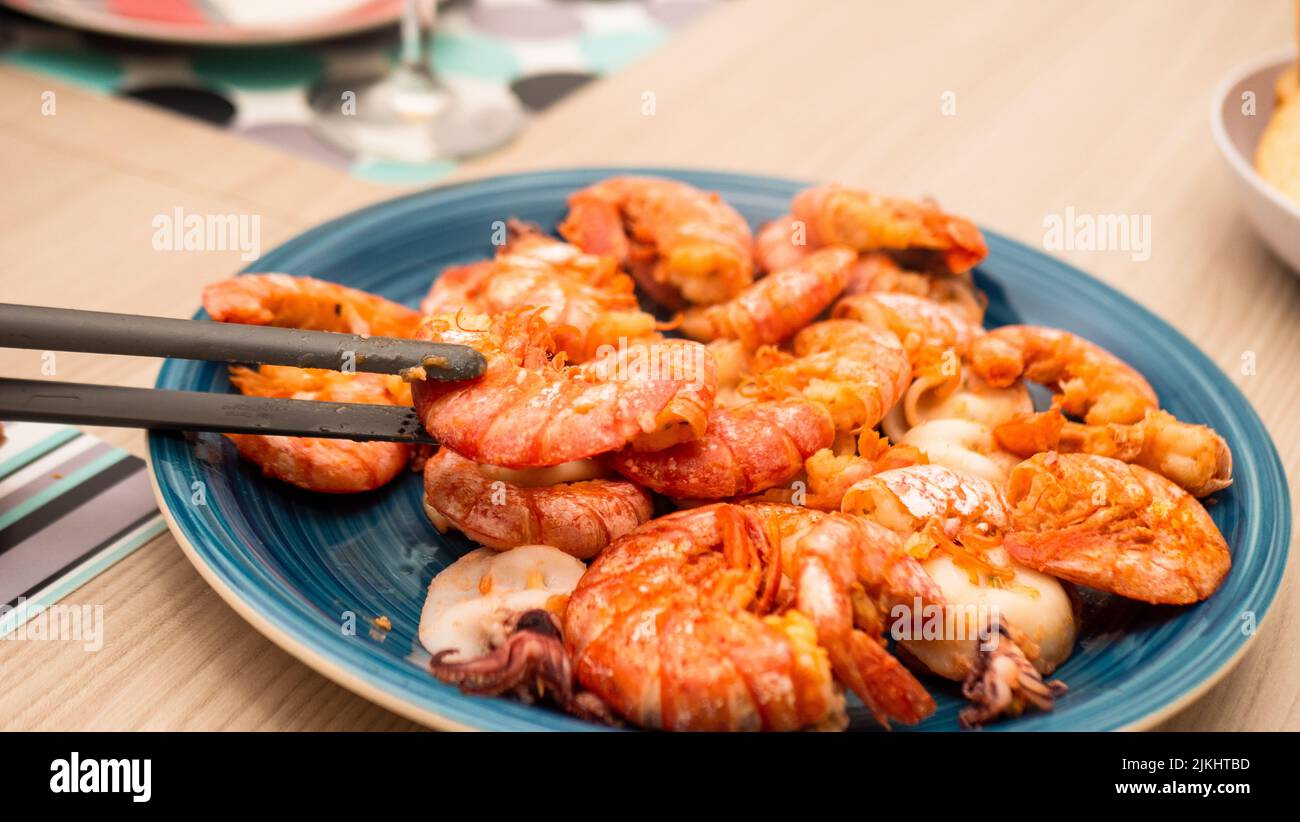 woman takes shrimp with tongs from a large plate of seafood Stock Photo ...