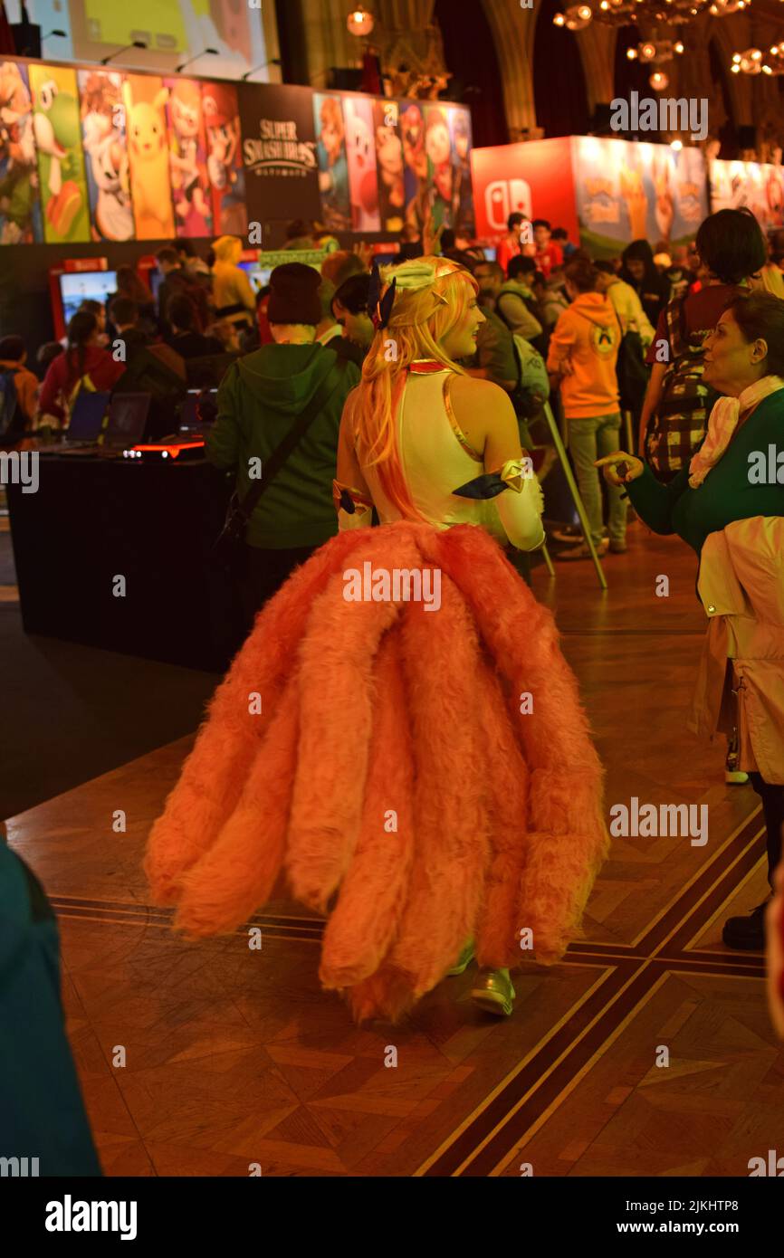 A vertical shot of a female in cosplay with many pink tails at a video ...
