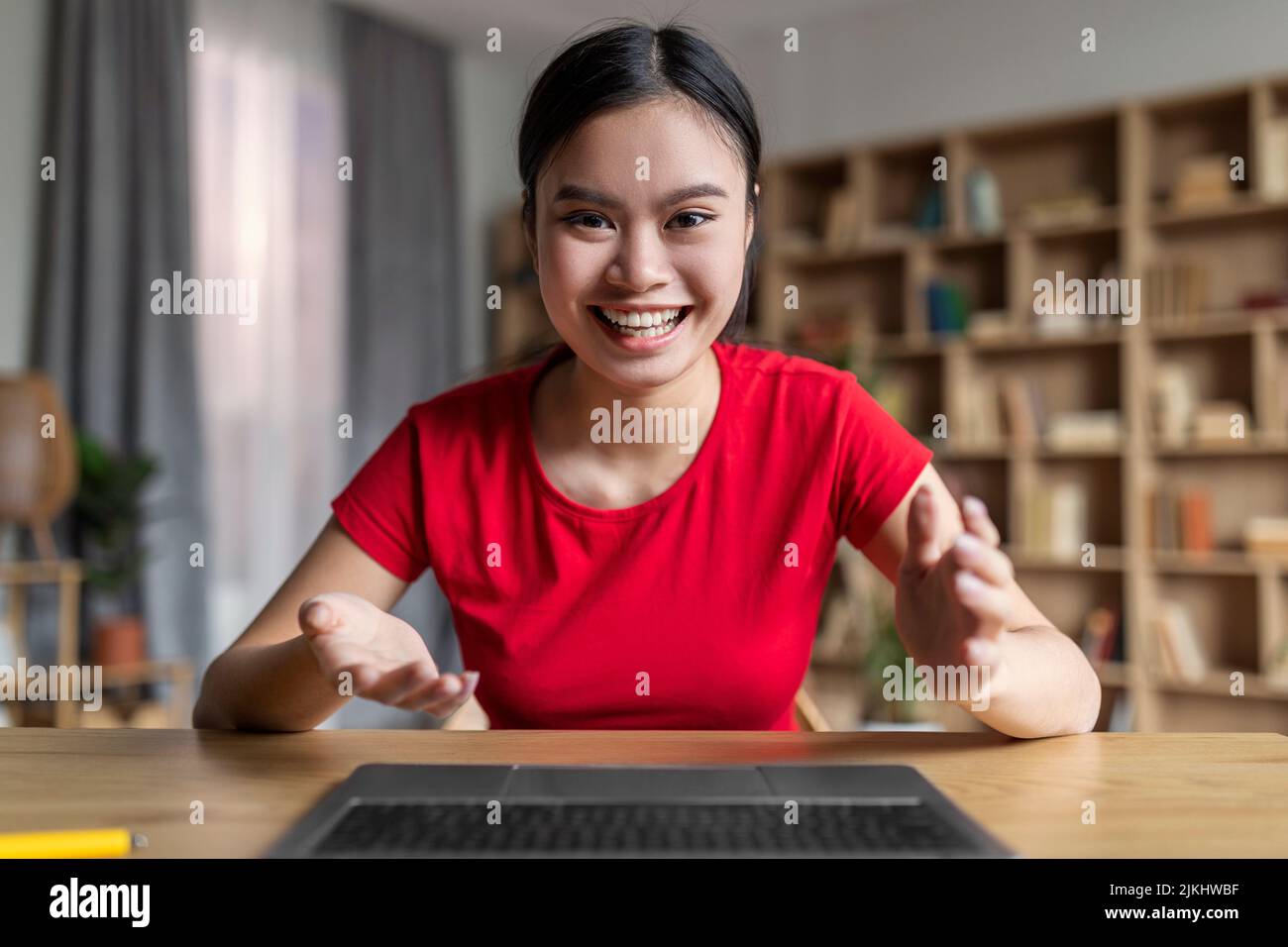 Glad excited young asian lady student rejoices and looks at computer ...