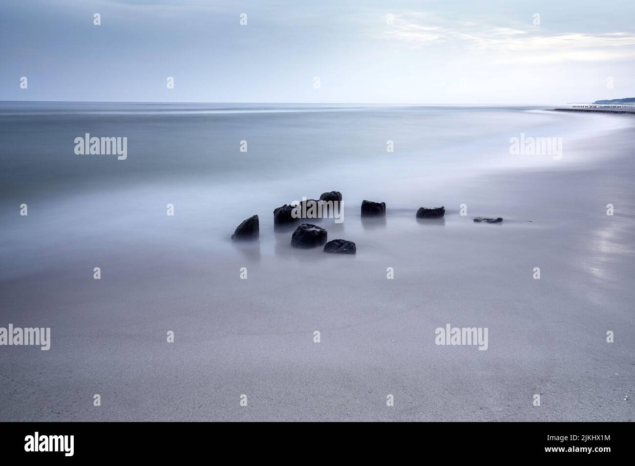 Some wooden stumps stuck in the sand on the beach Stock Photo - Alamy