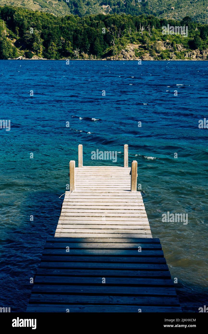 A view of a wooden jetty above the calm sea with mountains in the ...