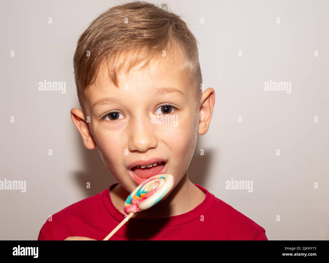 a boy eats a sweet multicolored candy on a stick, a boy with a lollipop ...