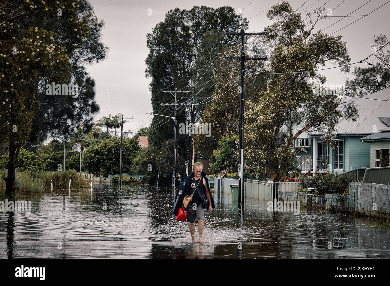 A man walking on a flooded road in the streets after a heavy rainy day ...