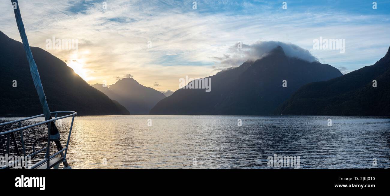 Sun rising over Doubtful Sound, Clouds hanging low on the mountains ...