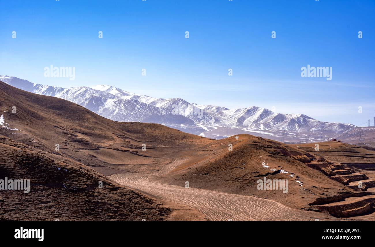 A deserted area and mountain range with snowy peaks in a distance Stock ...