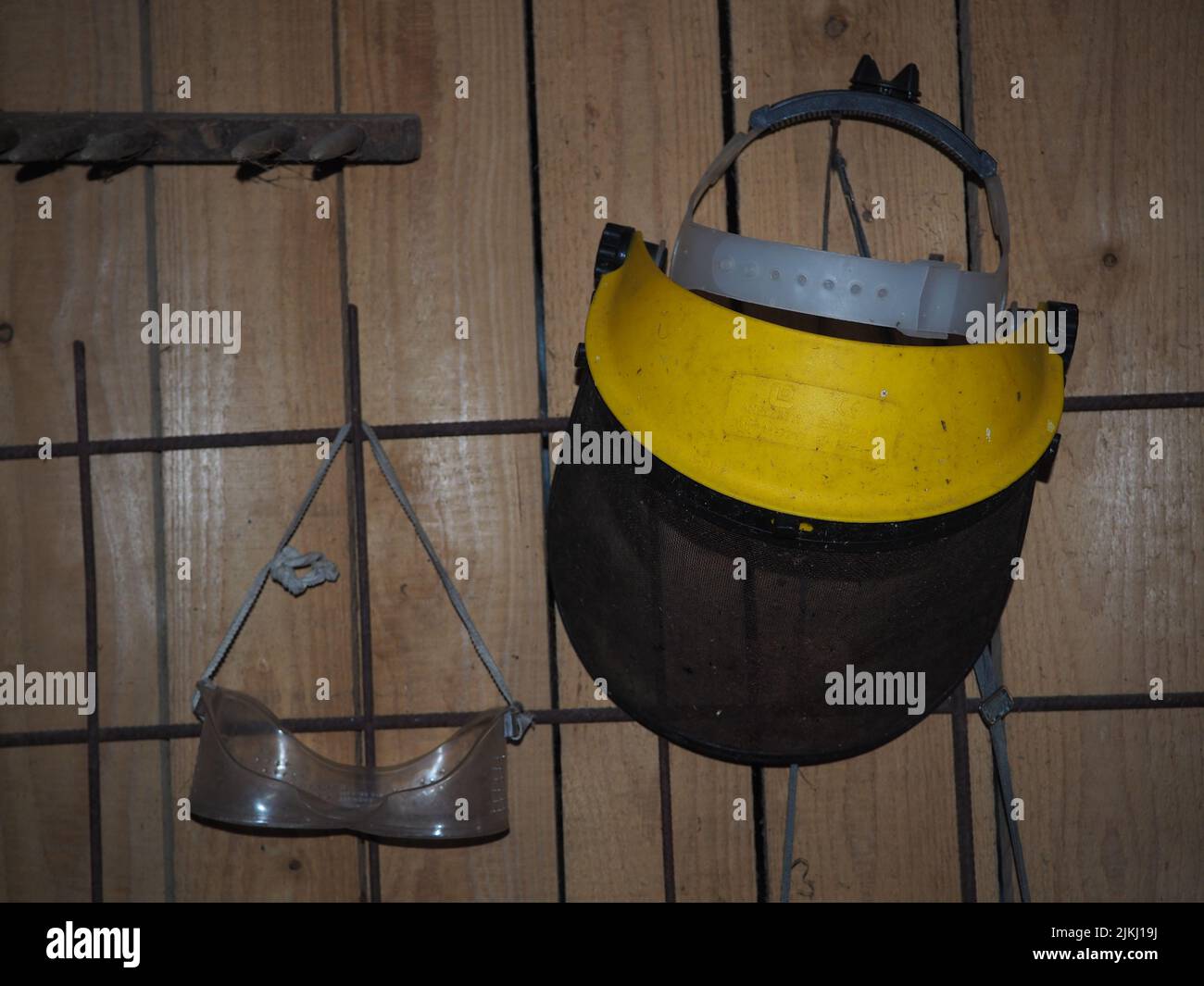 A closeup of a safety helmet with a face shield and goggles hanging on ...