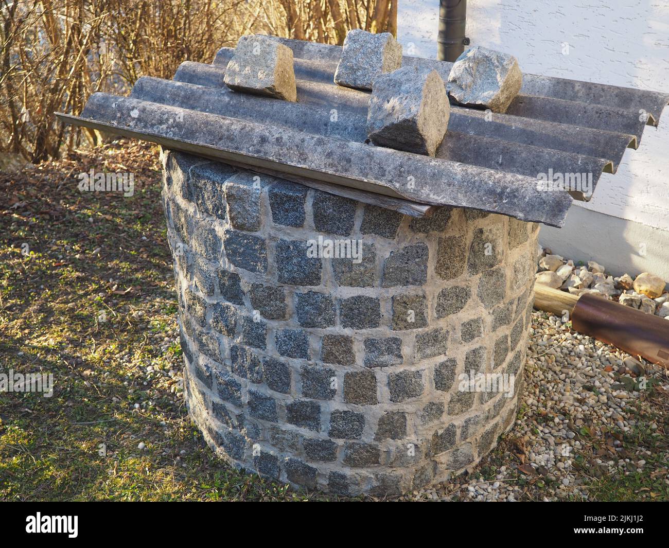A photo of a stone well with a zinc board and stones on top Stock Photo ...