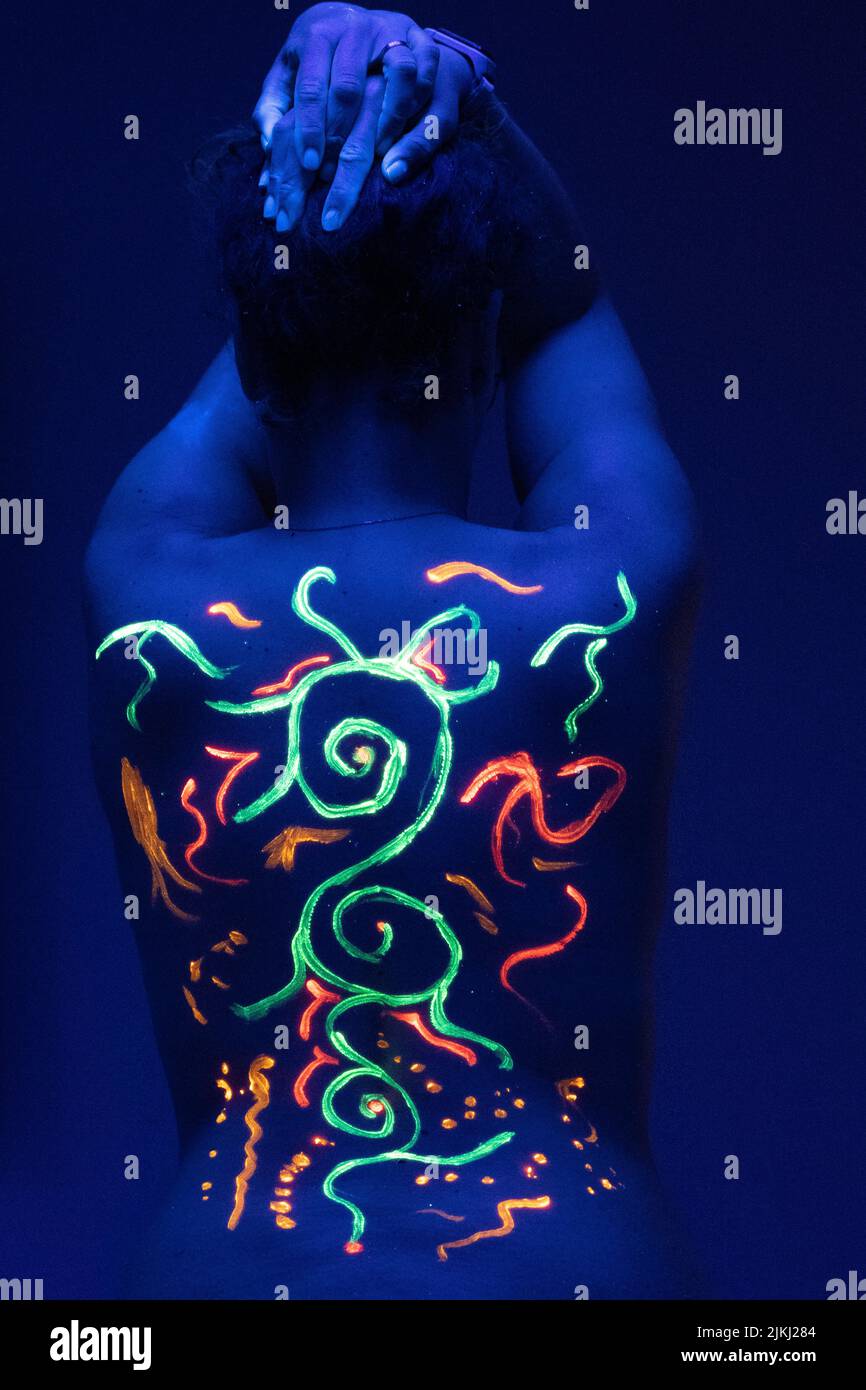 A vertical shot of a female back with colorful ethnic fluorescence ...