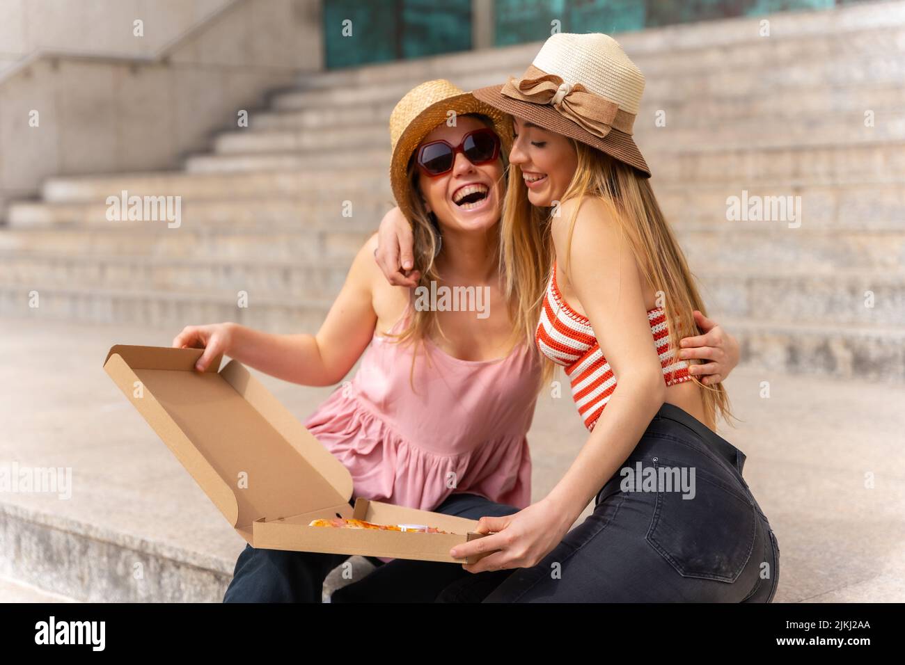 Friends eating pizza in the city enjoying the holidays, hugging and ...