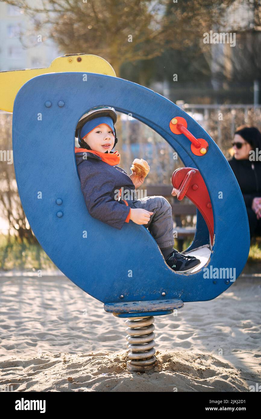 A little boy eating a snack while sitting in helicopter-shaped ...
