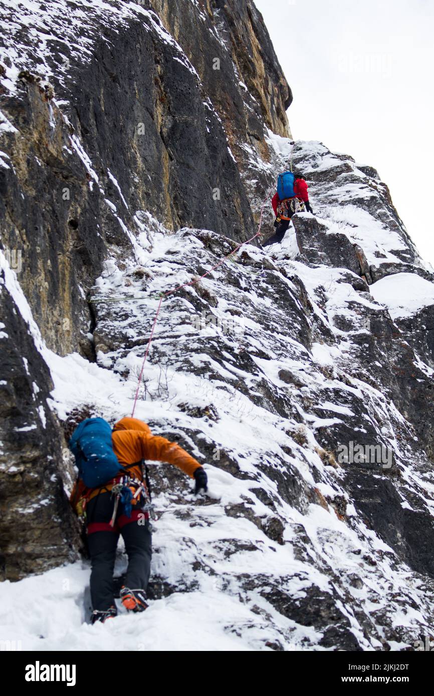 A vertical shot of two people climbing Mount Bourgeau in the Banff ...