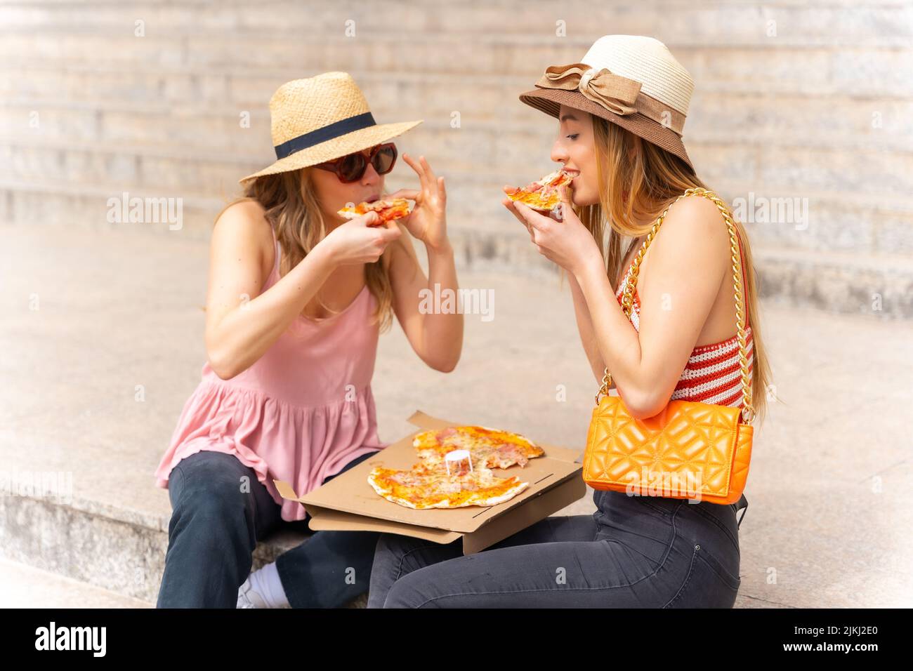 Friends eating pizza in the city enjoying the holidays, sitting on a ...