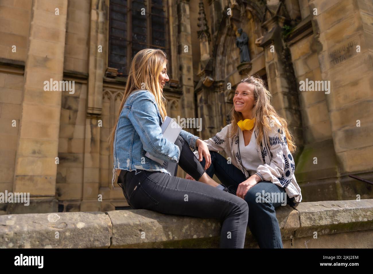 Two young Caucasian female friends in the city together with a book ...