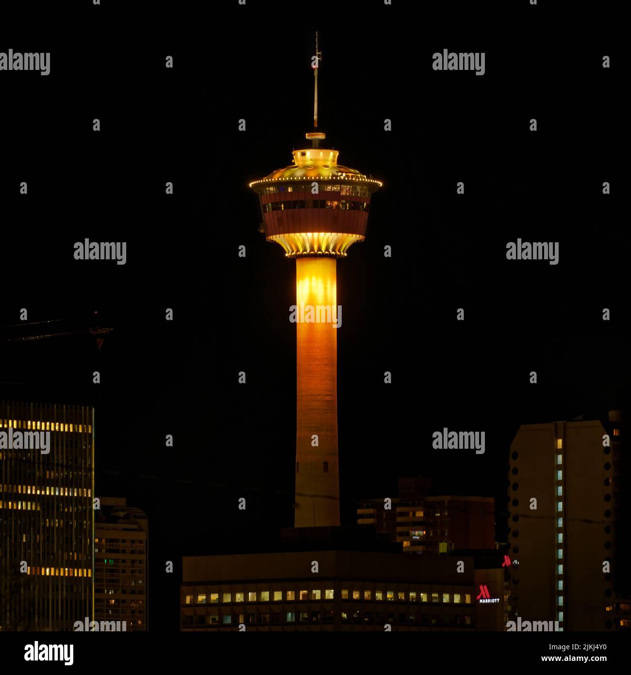 The bright Calgary Tower at night bathed in yellow and orange light in ...
