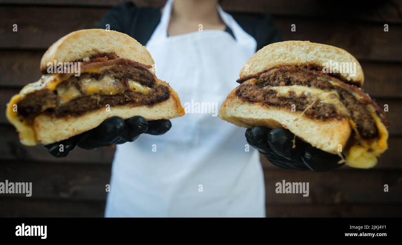A close-up shot of a chef holding a juicy burger in a cut in the ...
