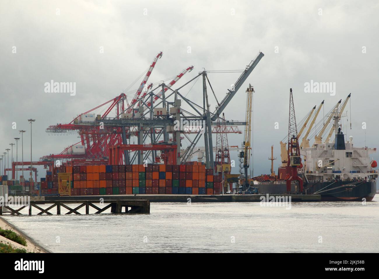 The cranes and cargo boxes near a boat on the harbor on the Tejo River ...