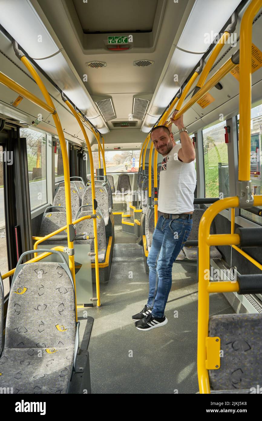 A vertical shot of a male passenger standing in an empty bus alone ...