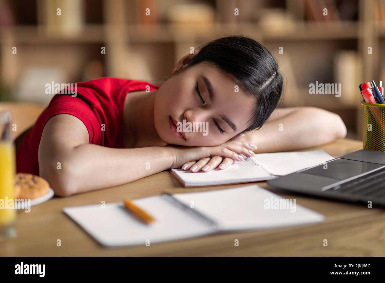 Bored tired young korean female student sleeping on desk with laptop in ...