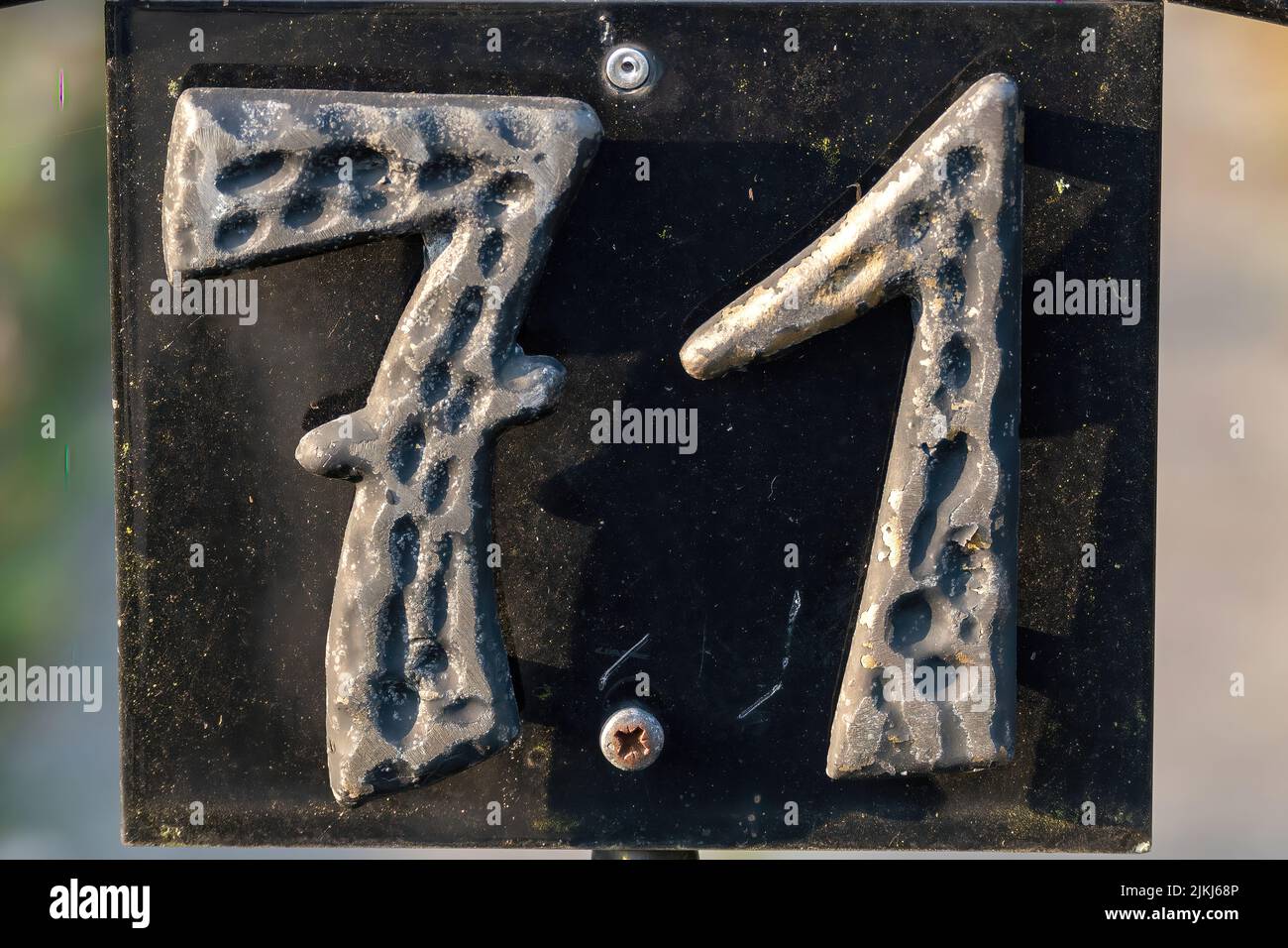 A closeup of an iron plate number 71 with a shadow outdoors Stock Photo ...