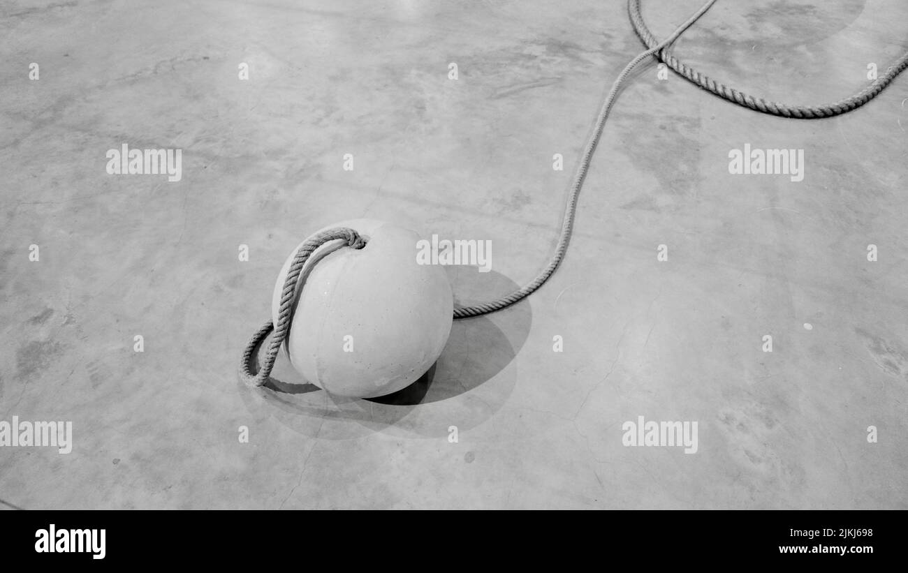 A grayscale of a sphere sculpture with a rope on the floor in Tate ...