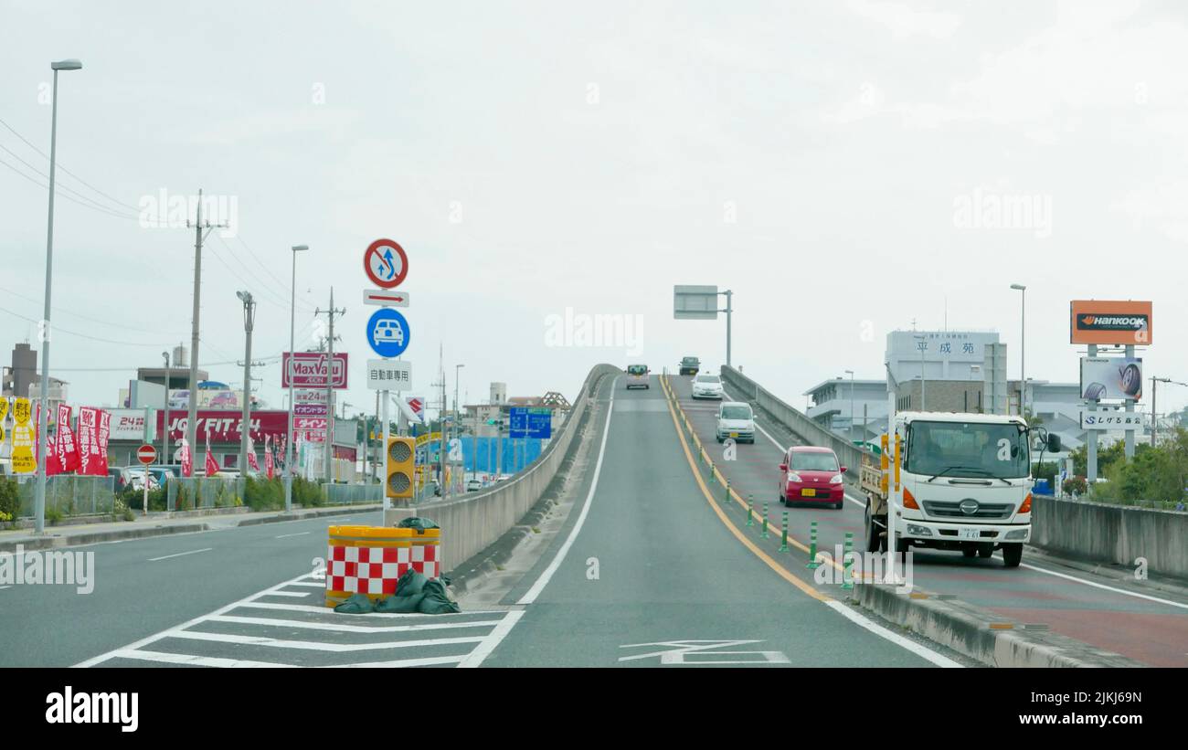A row of cars driving over a small bridge in Okinawa, Japan Stock Photo ...