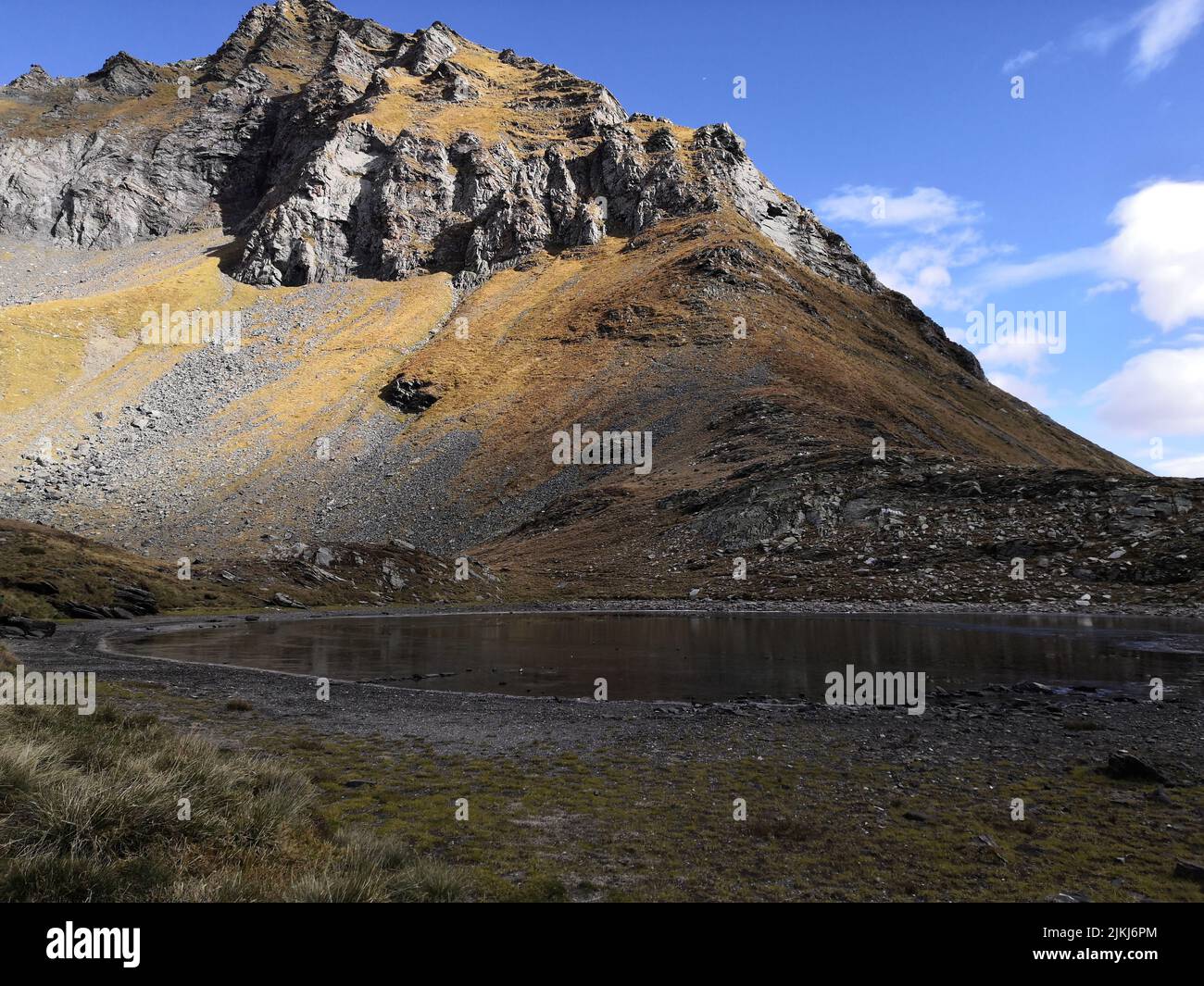 A view of a volcanic pond in the background of a huge cliff in the ...