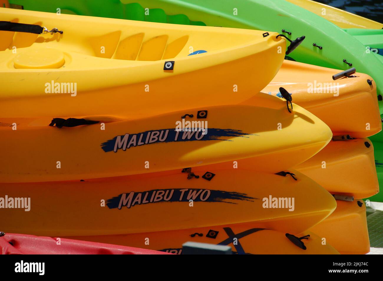 Many colorful kayaks laying on each other in the sunlight Stock Photo ...