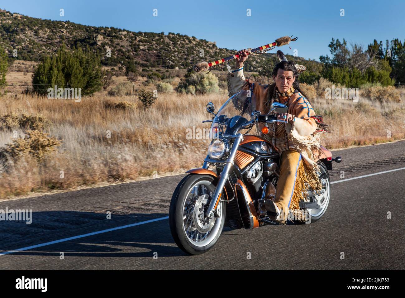 Traditionally dressed Native American man holds coupstick and rides ...