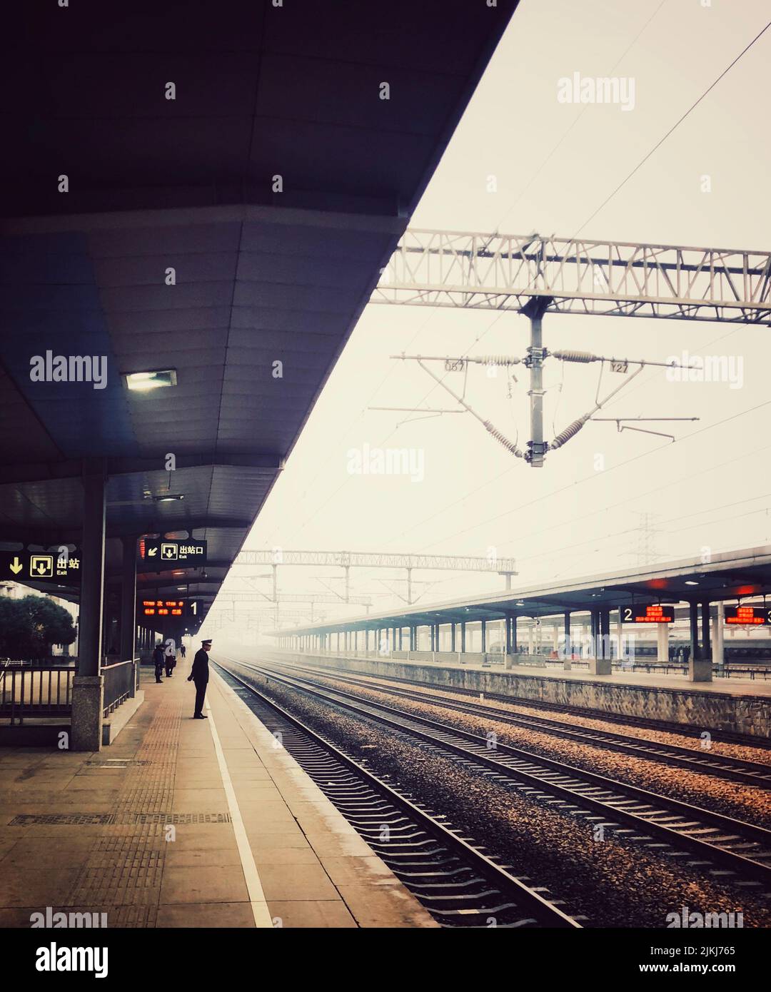 A vertical shot of a man waiting for the train alone at the railway ...