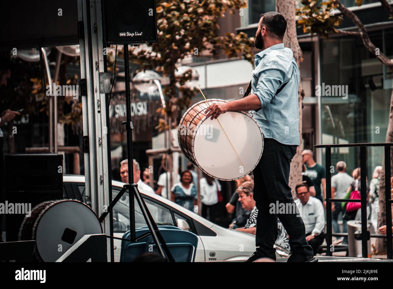 A man with a caucasian dhol standing on a stage during a concert ...