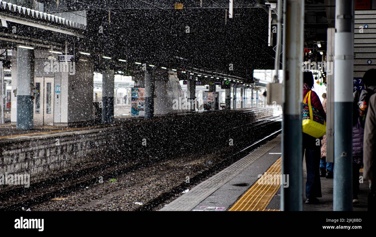 An old train station with people waiting beyond the yellow lane during ...