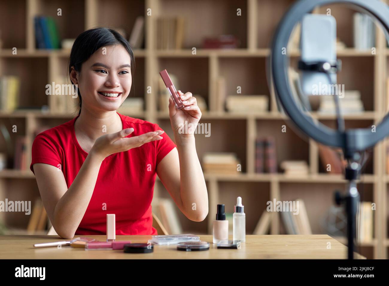 Cheerful young korean female blogger shows cosmetics, shooting vlog on ...