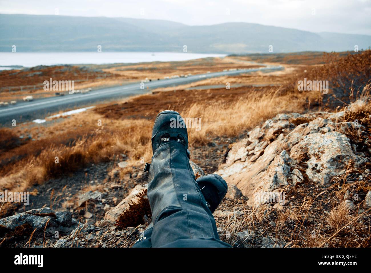 Legs of a man resting in black shoes for mountain tracking against the ...