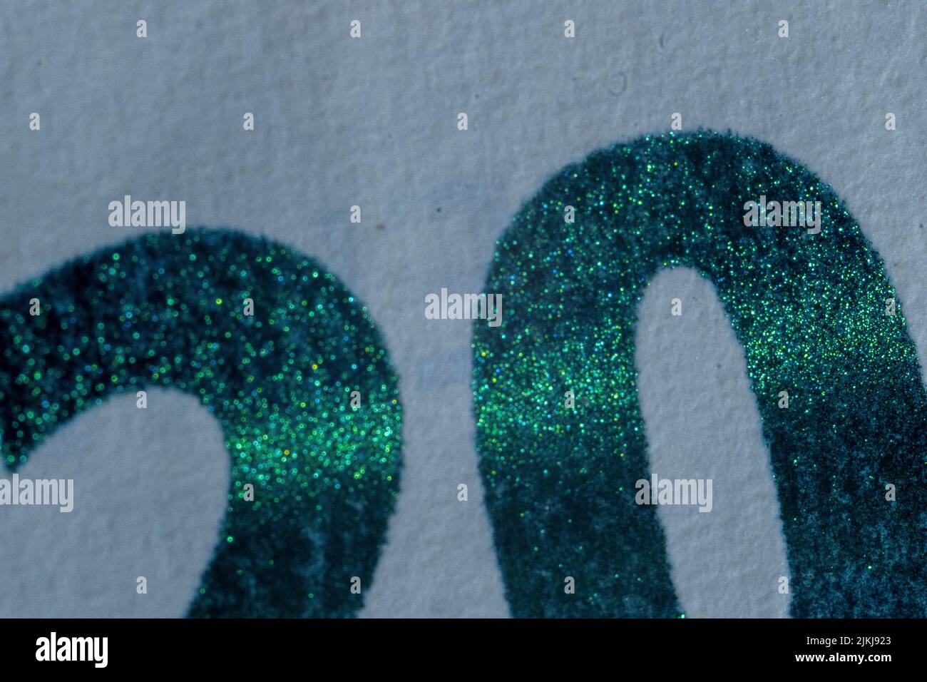 A macro focus shot of the green glitter ink of the number 20 on twenty ...