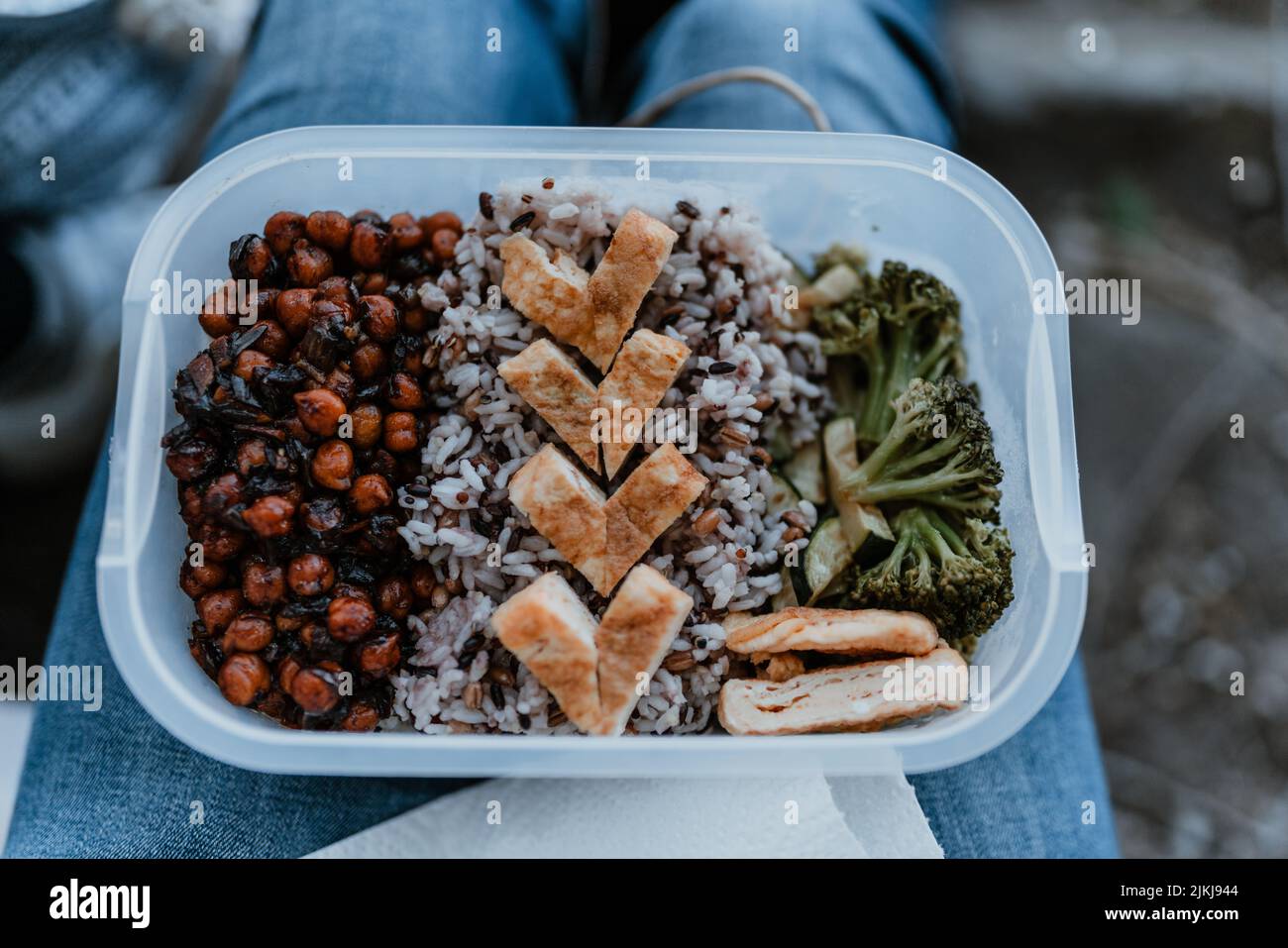 A shallow focus of a lunch box with chicken, rice, broccoli, and ...