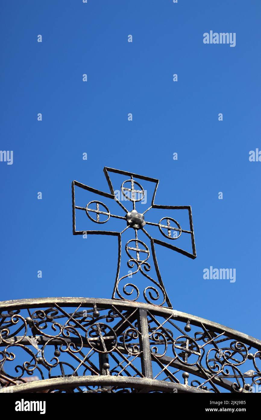 A low angle shot of an iron cross against blue sky in bright sunlight ...