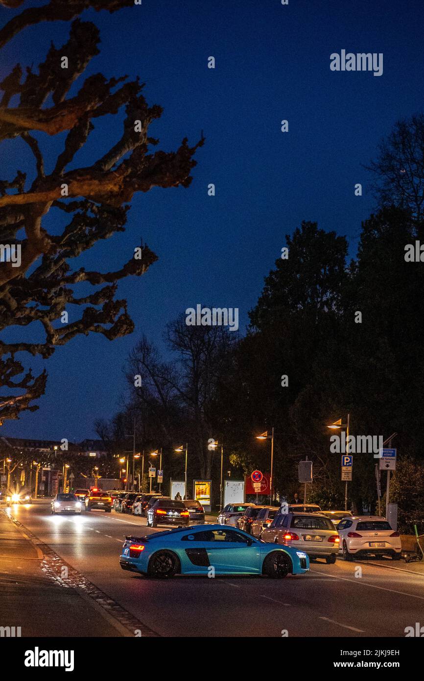 A vertical shot of a modern blue car in the street at night in the ...