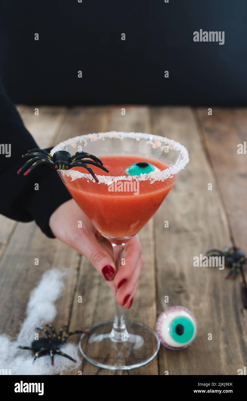 Terrifying red cocktail with spider on black background and wooden ...