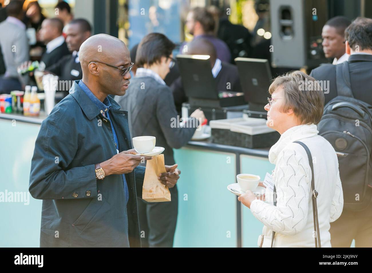 Two people networking at a business conference with a cup of coffee ...