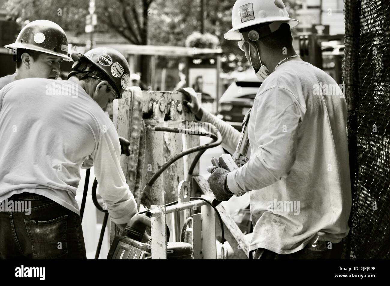 A grayscale shot of male workers with helmets working on something in ...