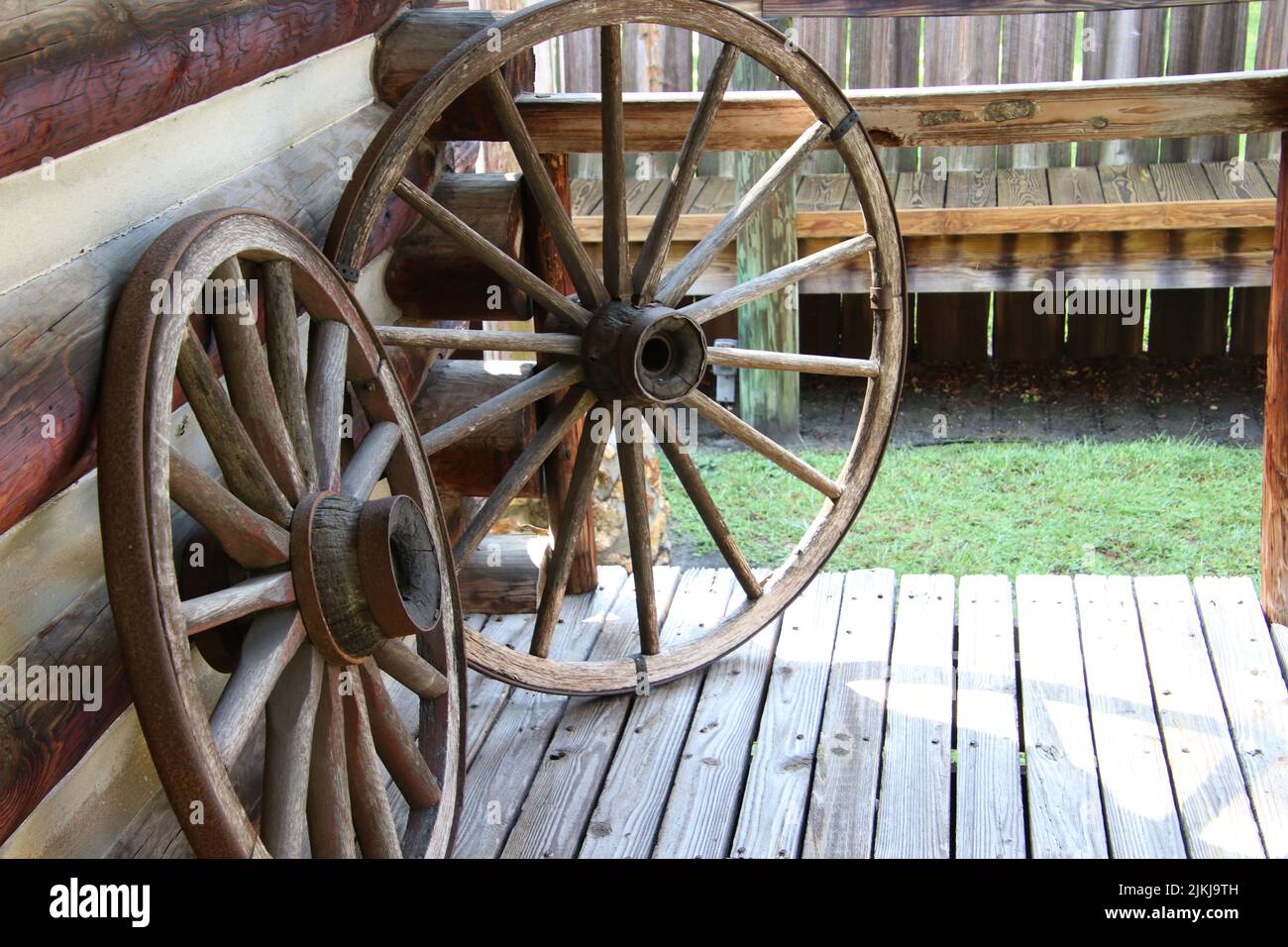A closeup of old fashion wagon wheels propped up against a log cabin at ...